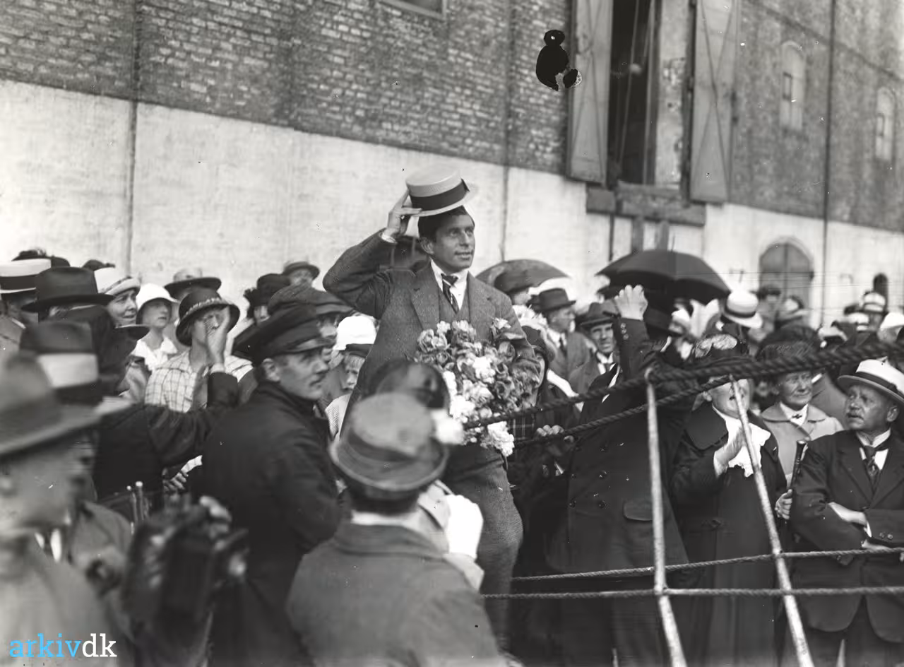 arkiv.dk | Afrejse til 5. Thule Ekspedition. Knud Rasmussen vinker med hatten, omgivet af ...