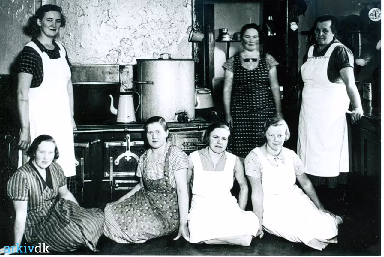 arkiv.dk | 7 kvinder i køkken, 4 siddende på gulvet. Gymnastikhøjskolen i Ollerup, 1937